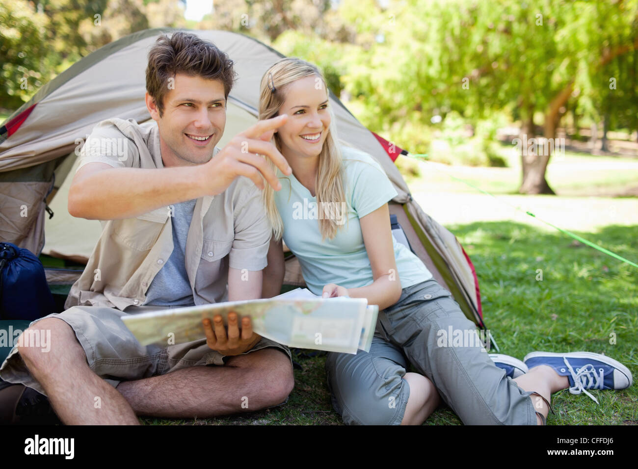 A man and his girlfriend hold a map while the man points something out ...