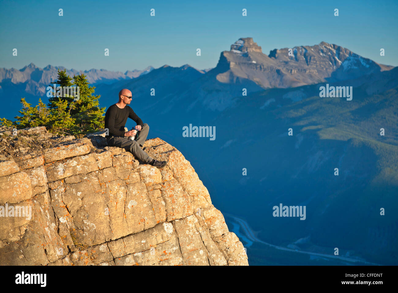 A hiker sits on a cliff edge, Banff National Park, Alberta, Canada ...