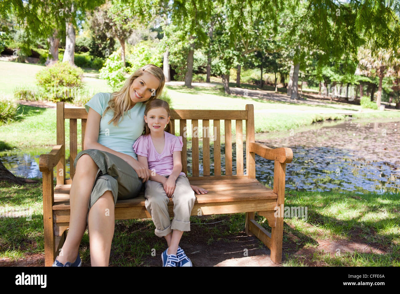 A mom and daughter smile while sitting on a bench in the park Stock ...