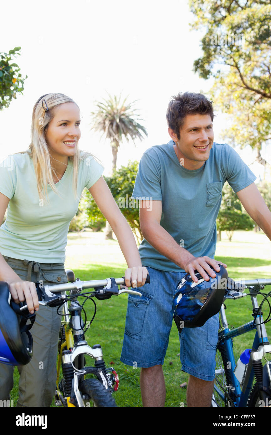 A couple standing beside their bikes smiling Stock Photo - Alamy