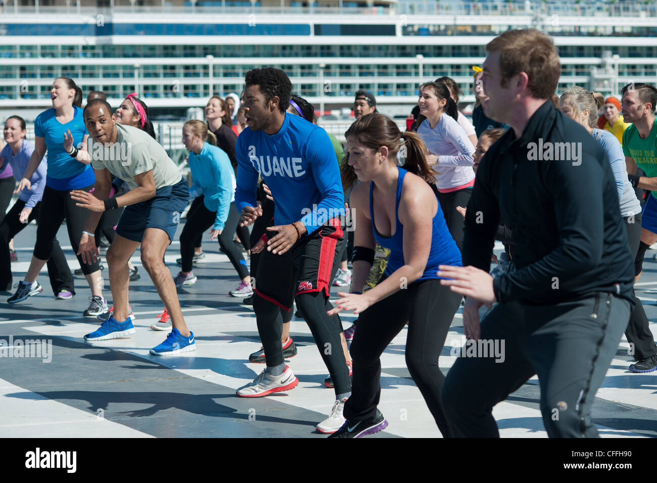 Exercisers participate in an exercise class on the flight deck of the ...