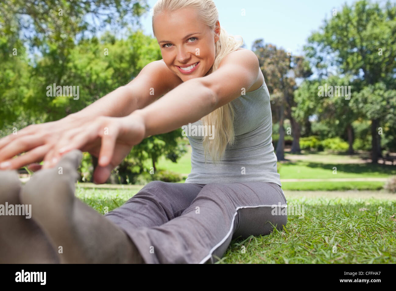 Smiling sportswoman stretching on the grass Stock Photo - Alamy