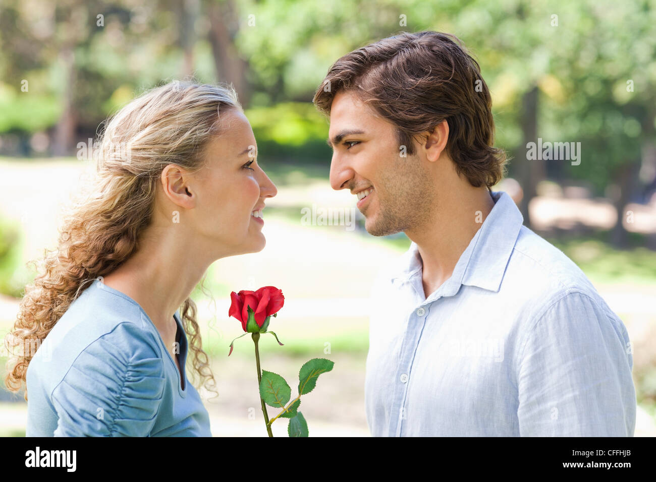Side view of a man offering a rose to his girlfriend Stock Photo - Alamy