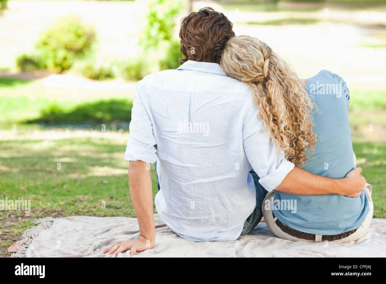 Back view of a couple sitting on the lawn Stock Photo - Alamy