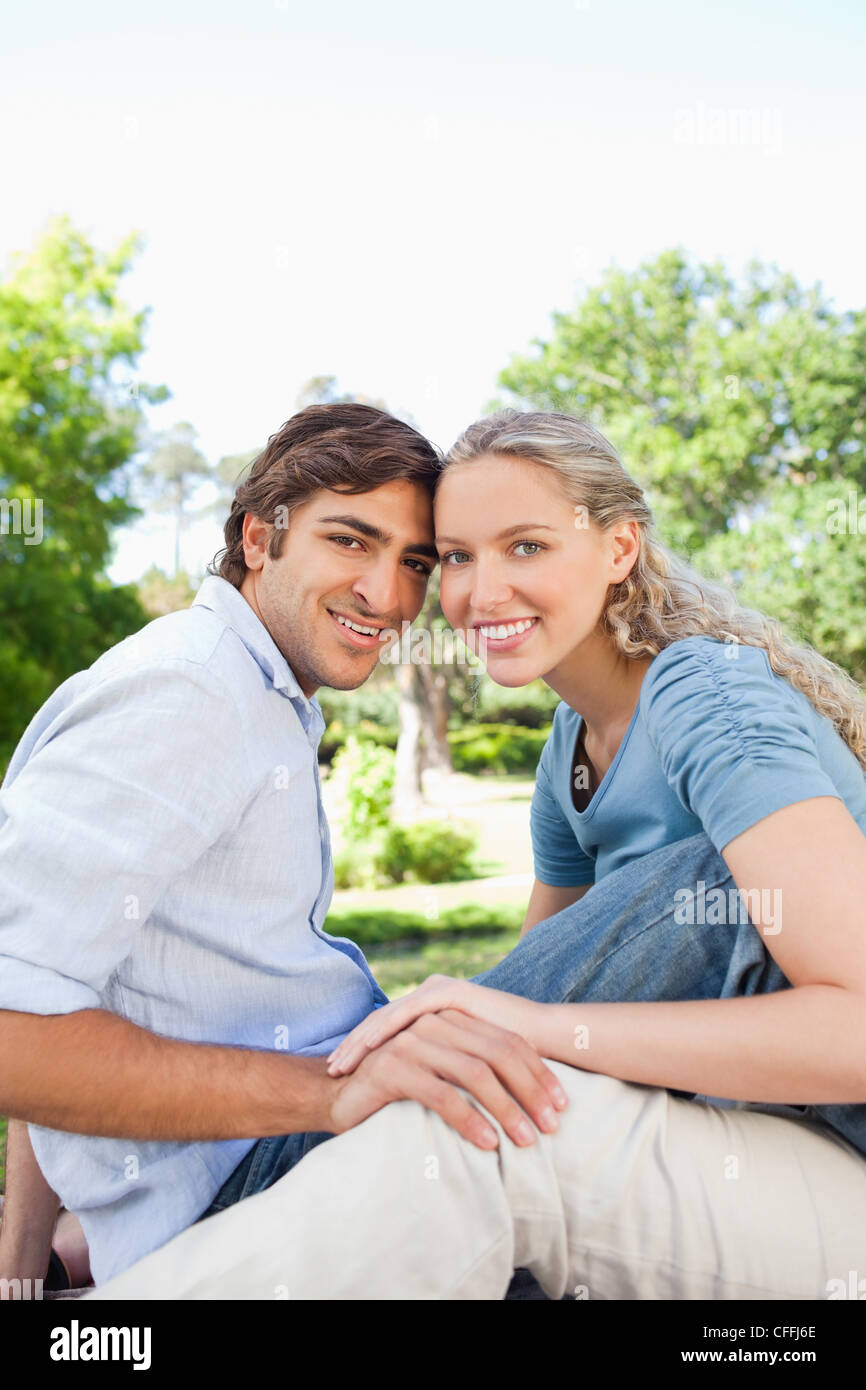 Smiling couple sitting close together in the park Stock Photo - Alamy