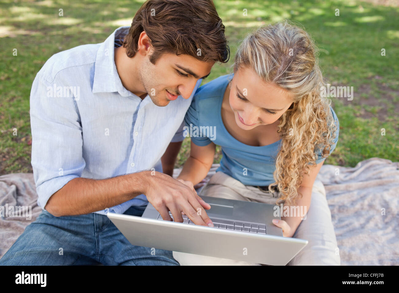 Couple using their laptop in the park Stock Photo - Alamy