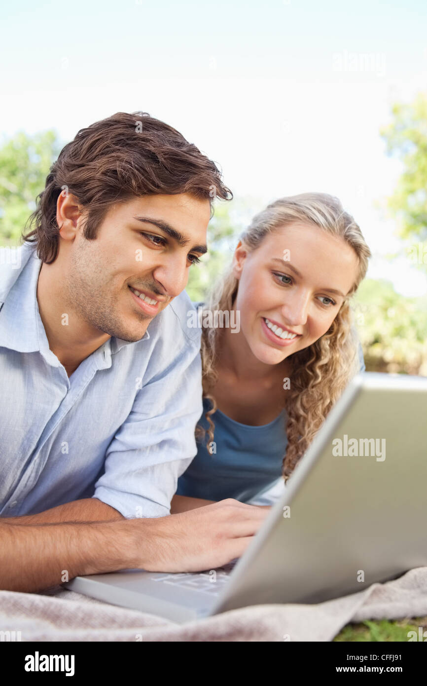 Smiling couple using their laptop on the lawn Stock Photo - Alamy
