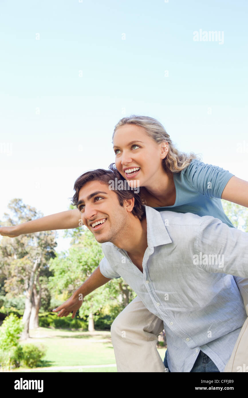 Side view of a man carrying his his friend on his back while she ...