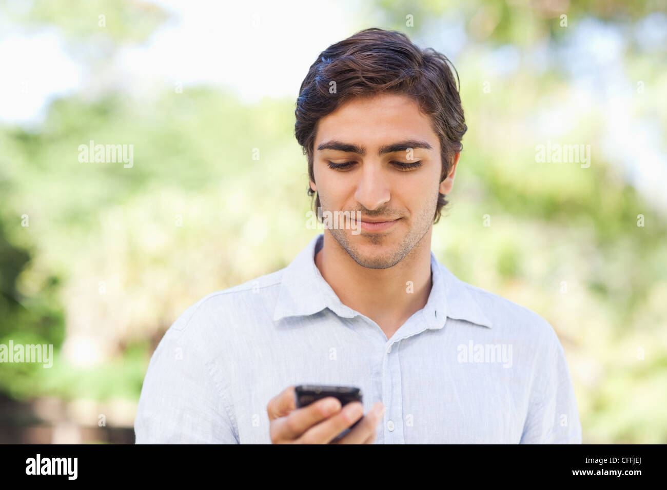 Man looking at his cell phone in the park Stock Photo - Alamy