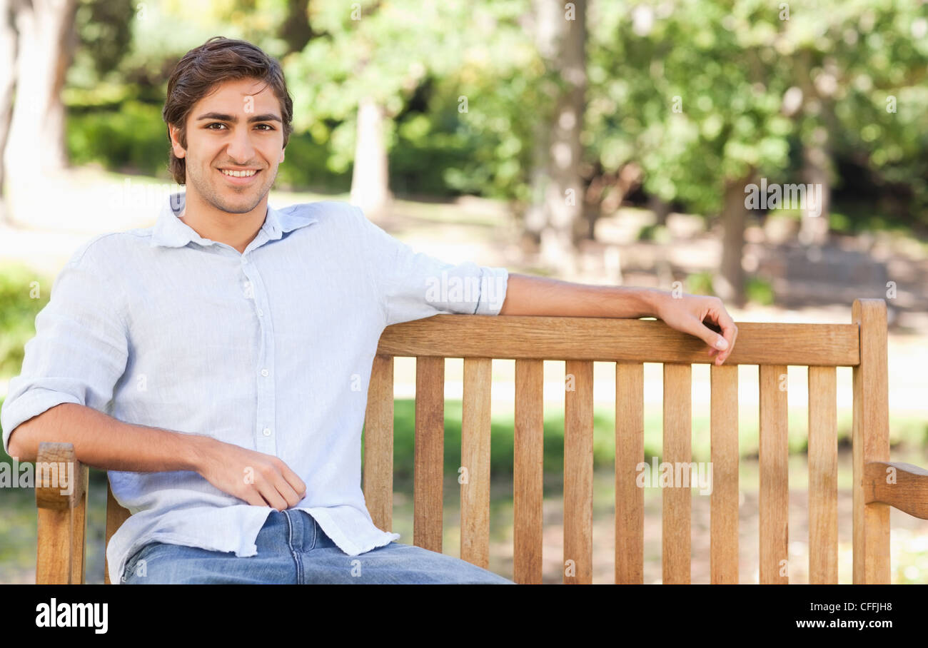Smiling man sitting on a bench Stock Photo - Alamy