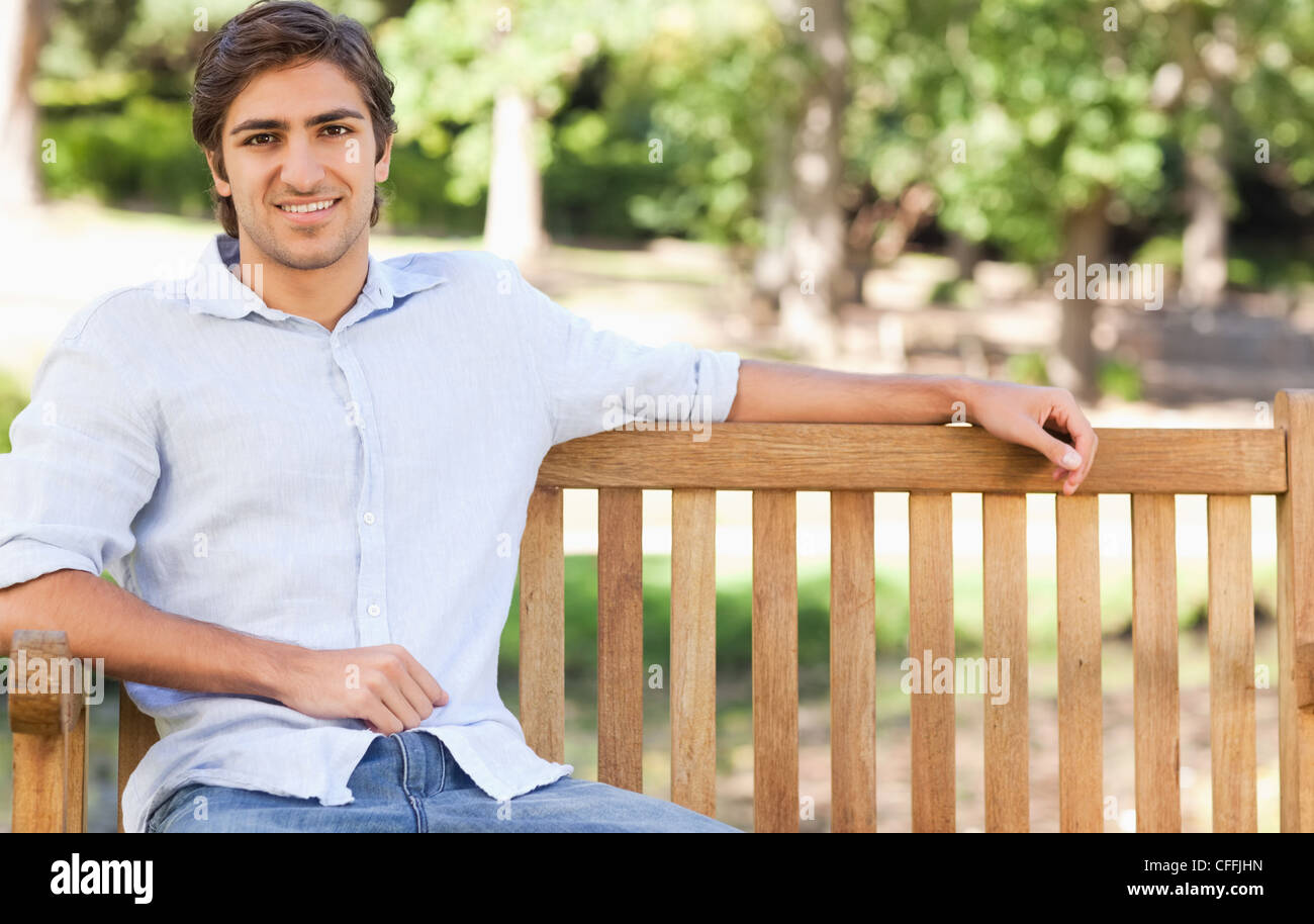 Smiling man sitting on a bench in the park Stock Photo - Alamy