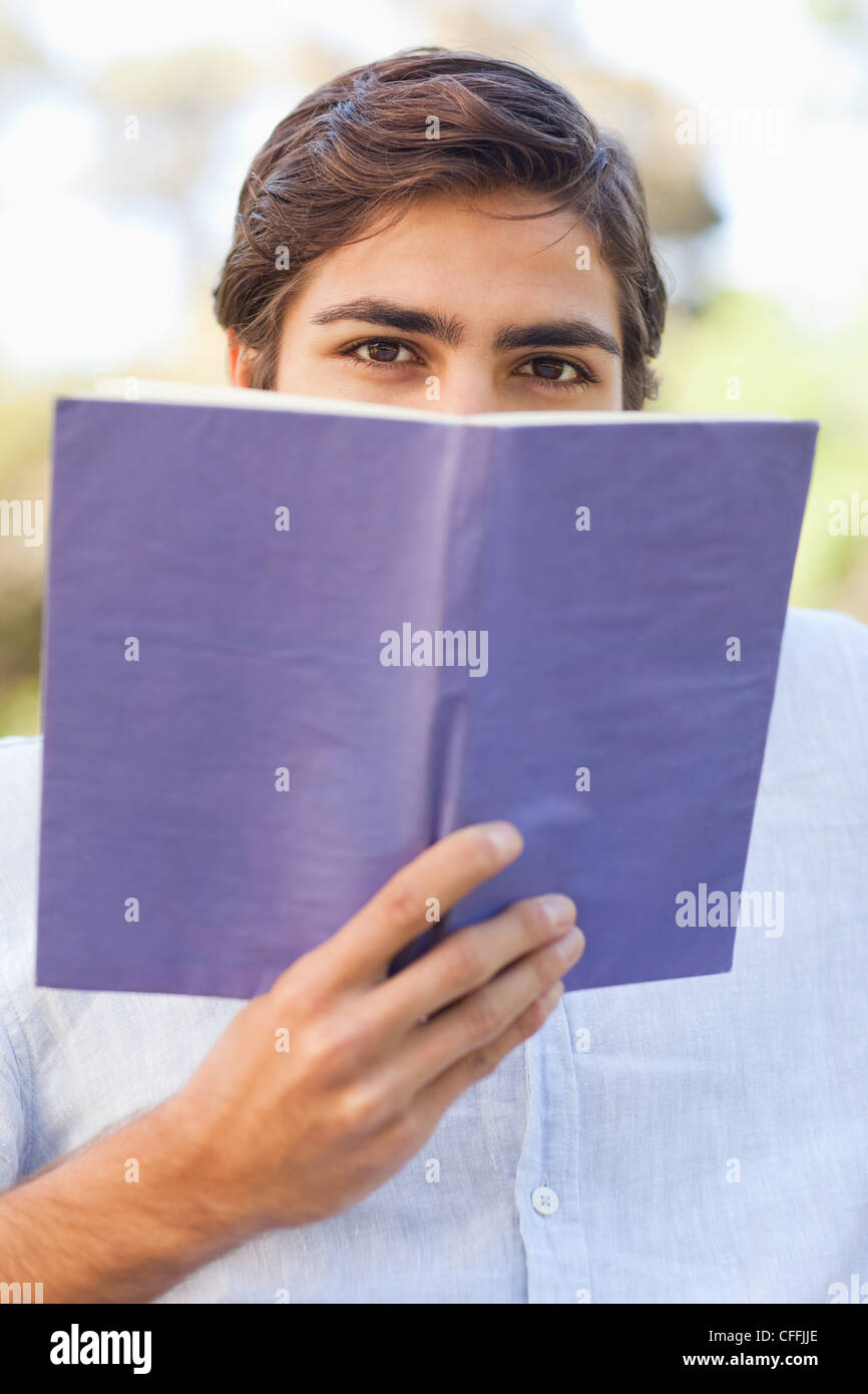 Man hiding his face behind his book Stock Photo - Alamy