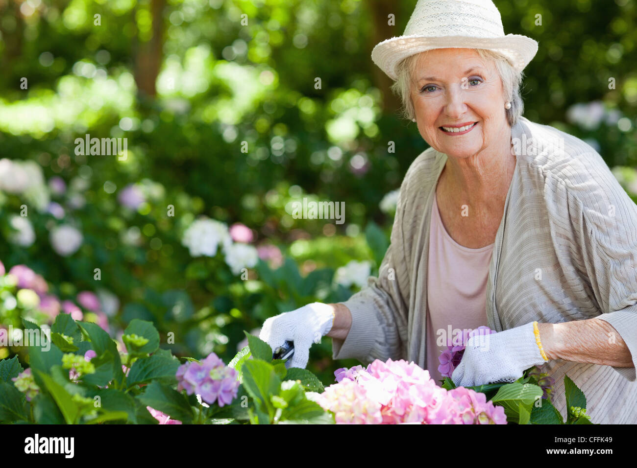 Woman smiling and looking ahead while pruning flowers Stock Photo - Alamy