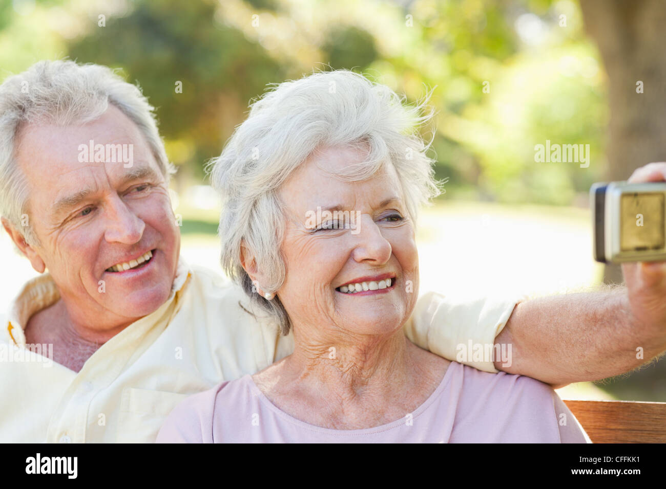 Two friends smiling as they pose for a picture on a bench Stock Photo ...
