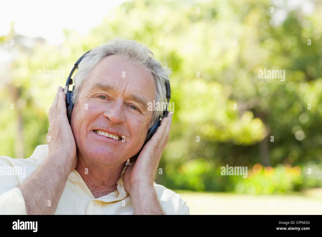 Man smiling as he uses headphones to listen to music Stock Photo - Alamy