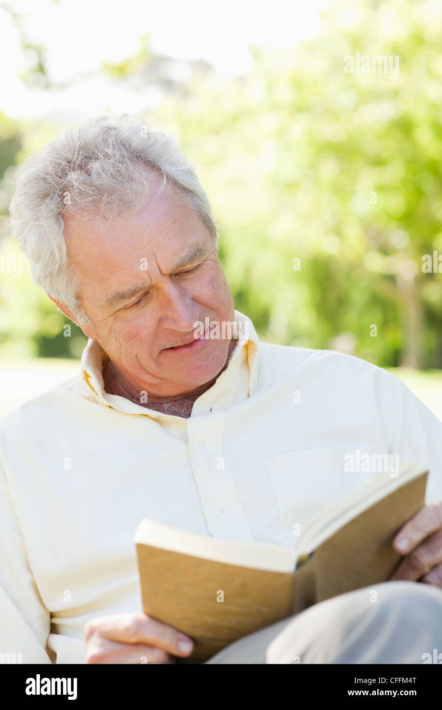 Man smiling while reading a book in a park Stock Photo - Alamy