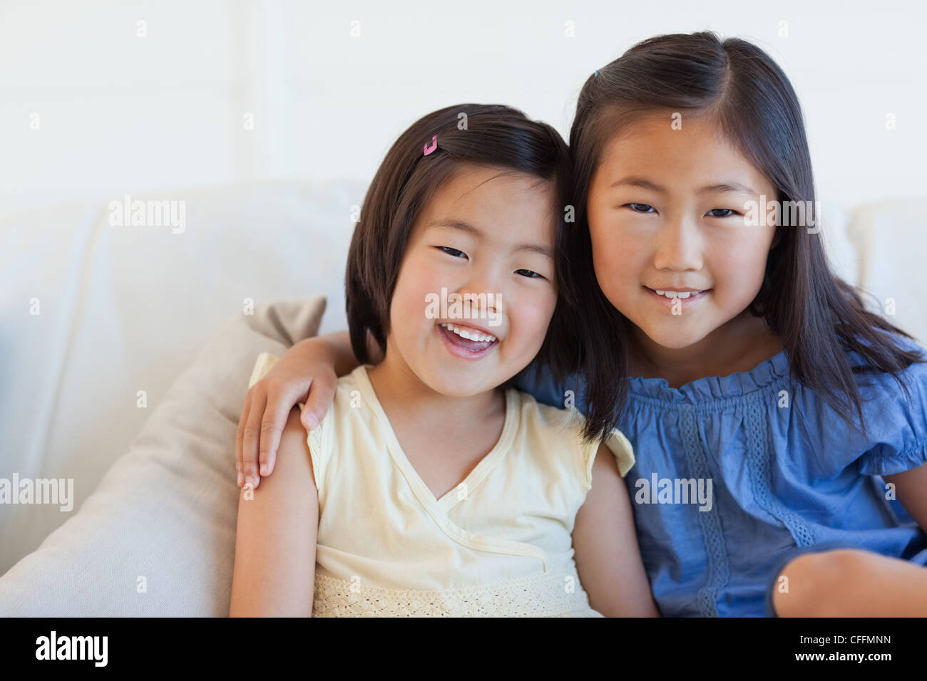 Two girls sitting beside each other, with one girls arm around the ...