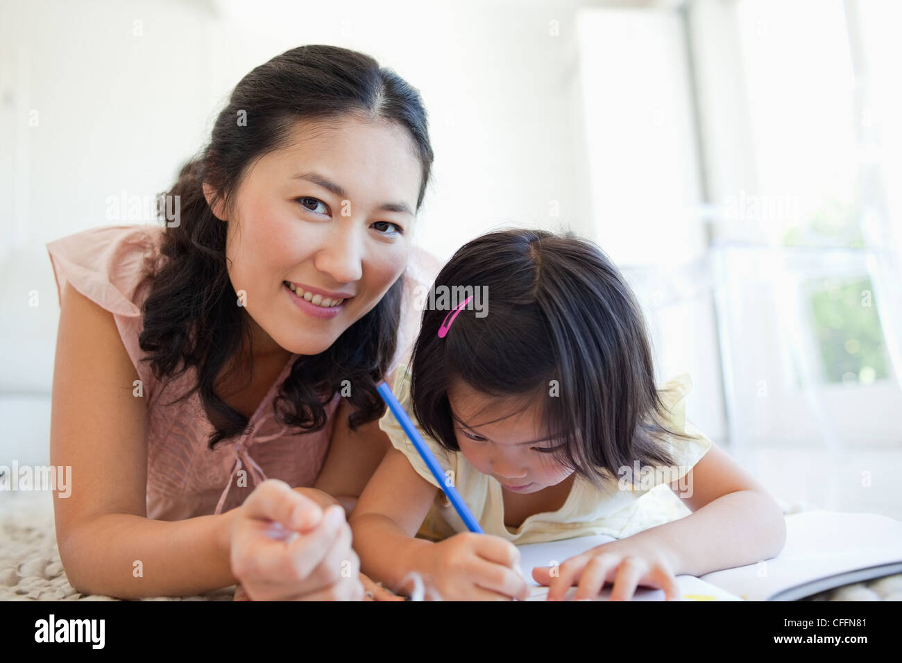 A mother smiles as her daughter colours Stock Photo - Alamy
