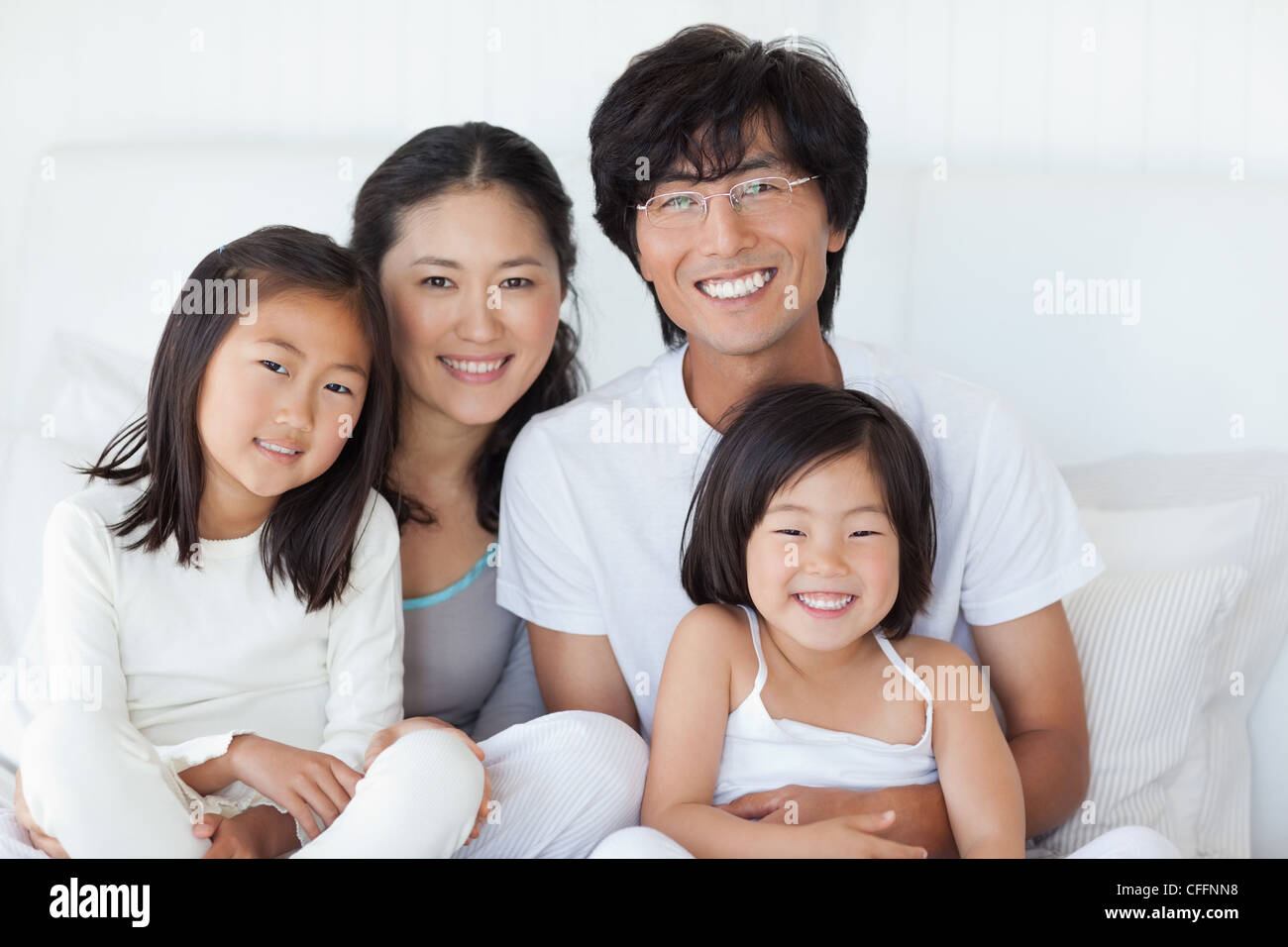 The entire family happily sitting on the bed together Stock Photo - Alamy