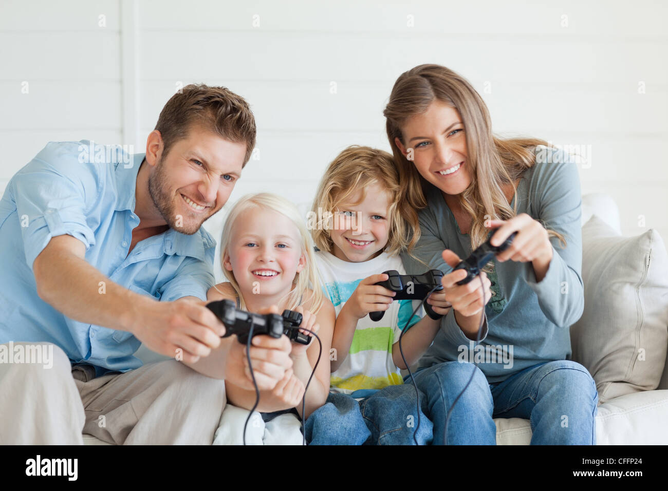 A family playing a games console together as they sit on the couch ...