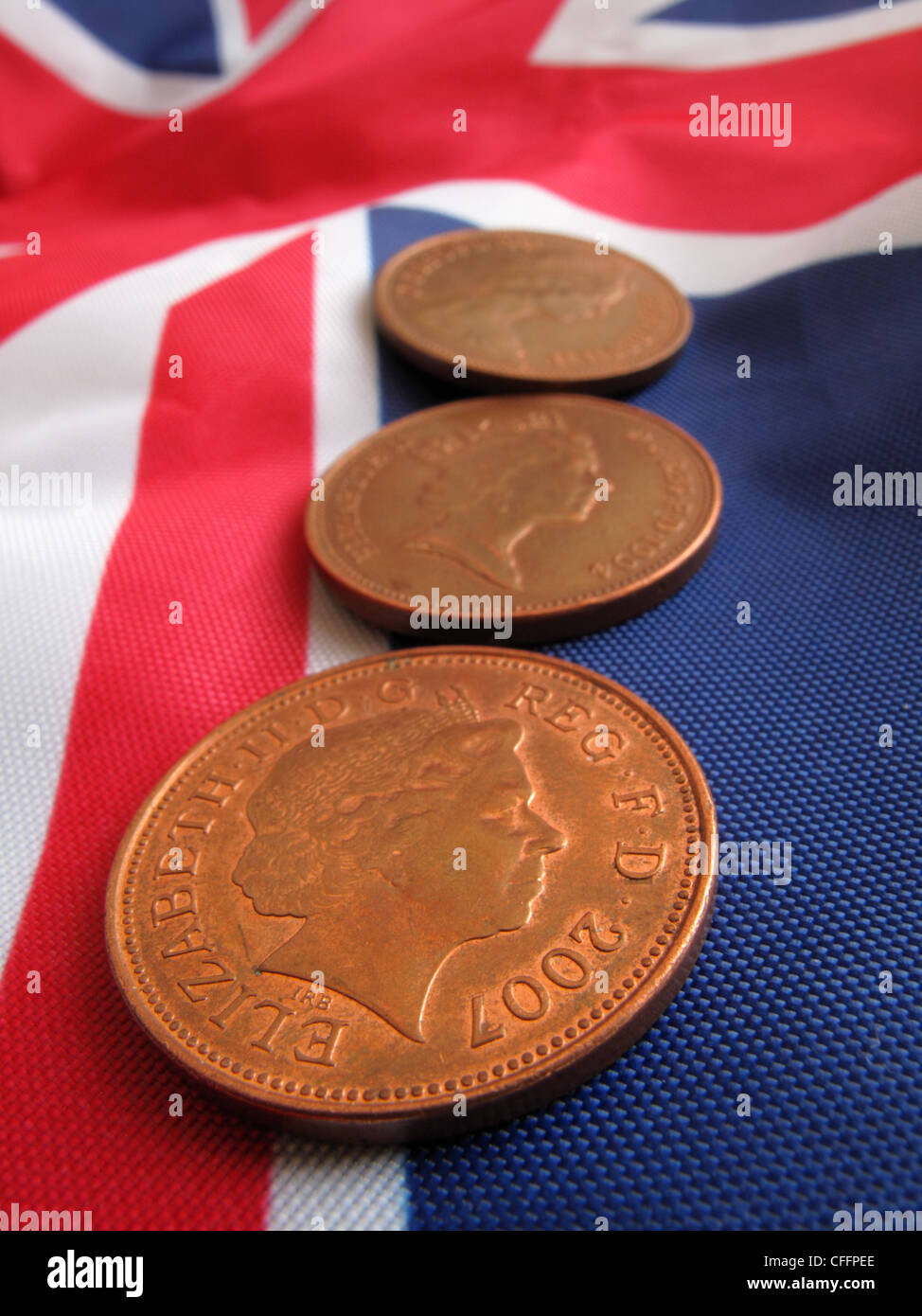 Three copper coins set against a union jack flag , showing the queens ...