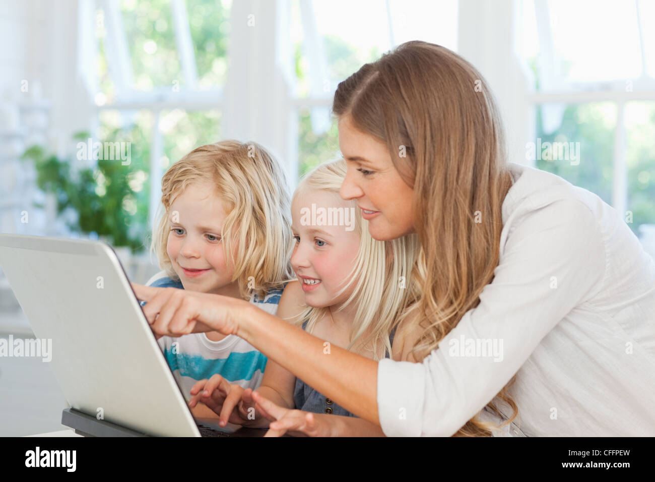 Mother and her children use a laptop in the living room Stock Photo - Alamy