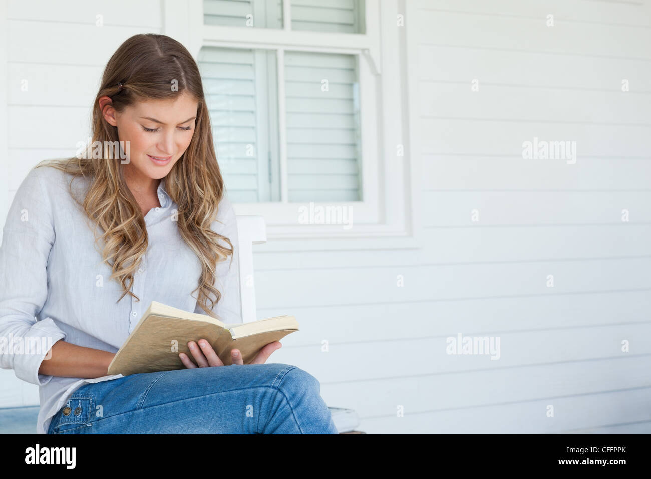 Woman reading a book outside the house Stock Photo - Alamy