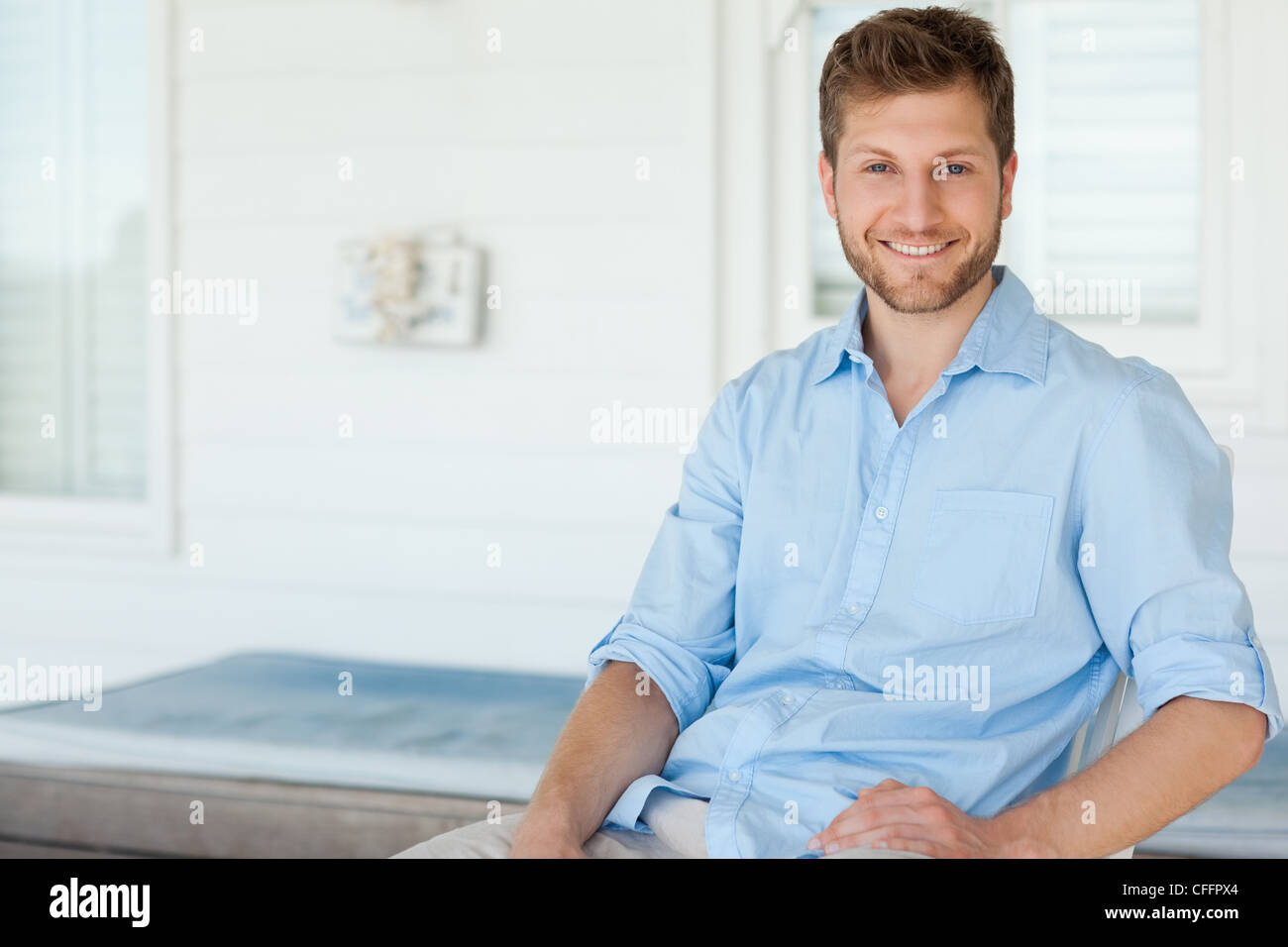 Smiling man sits outside in the porch Stock Photo - Alamy