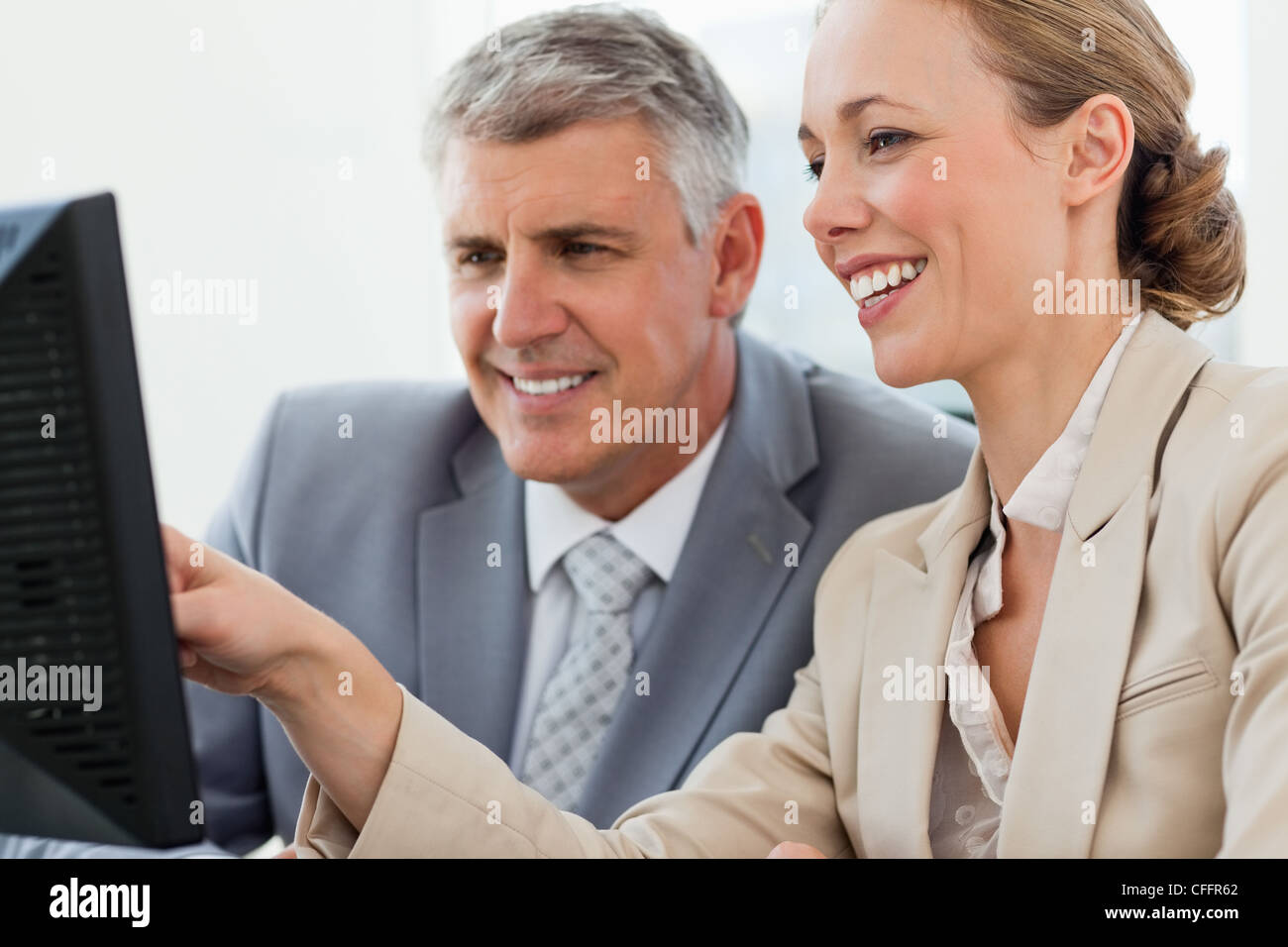 Business people smiling while looking a computer screen Stock Photo - Alamy