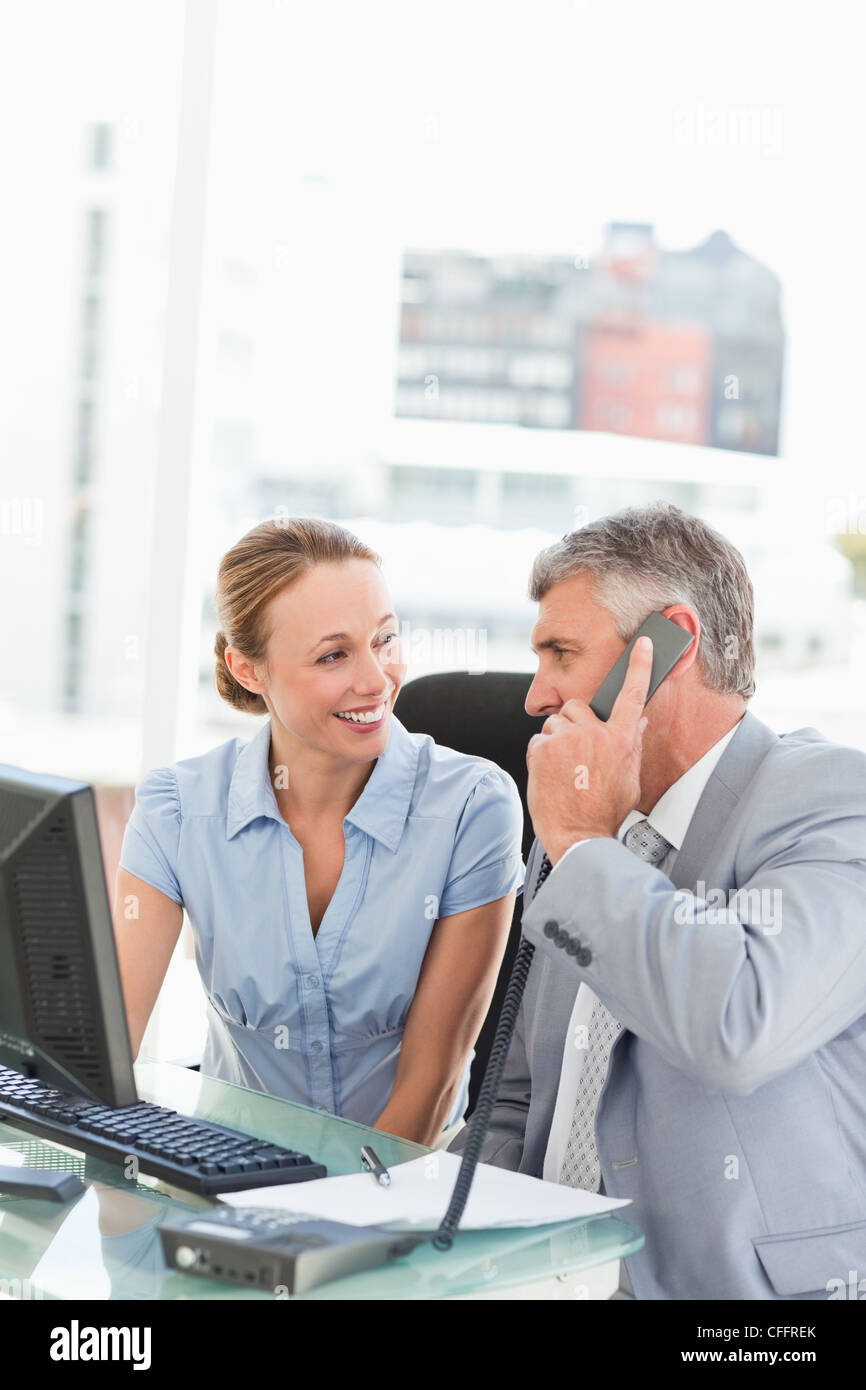 Boss on the phone while smiling to an employee Stock Photo - Alamy