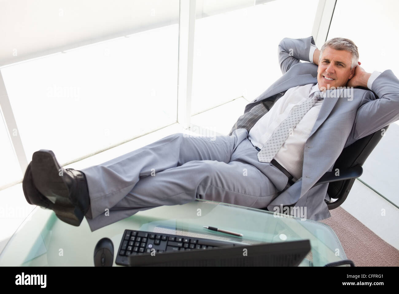 Portrait of a smiling boss with feet on his desk Stock Photo - Alamy
