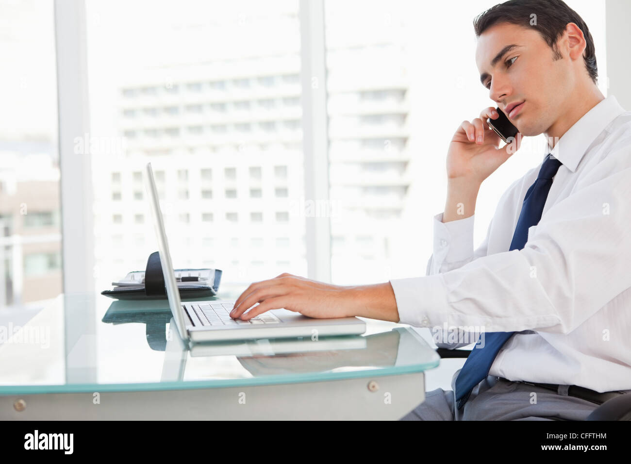 Businessman calling while tapping his laptop Stock Photo - Alamy