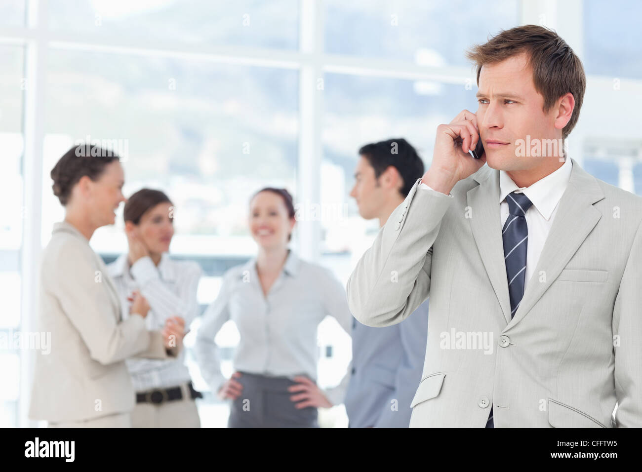 Salesman on his cellphone with colleagues behind him Stock Photo - Alamy