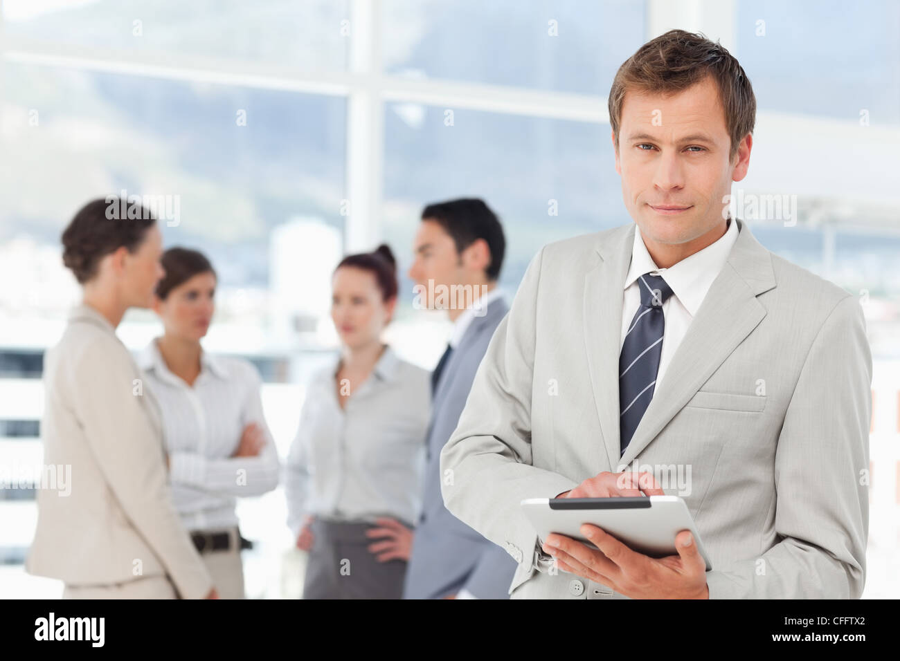 Salesman with tablet computer and colleagues behind him Stock Photo - Alamy