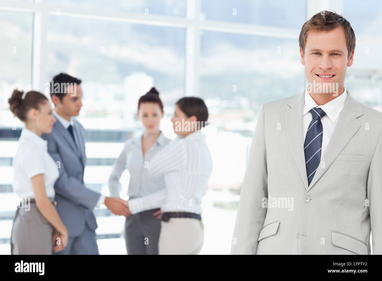 Smiling salesman with colleagues behind him Stock Photo - Alamy