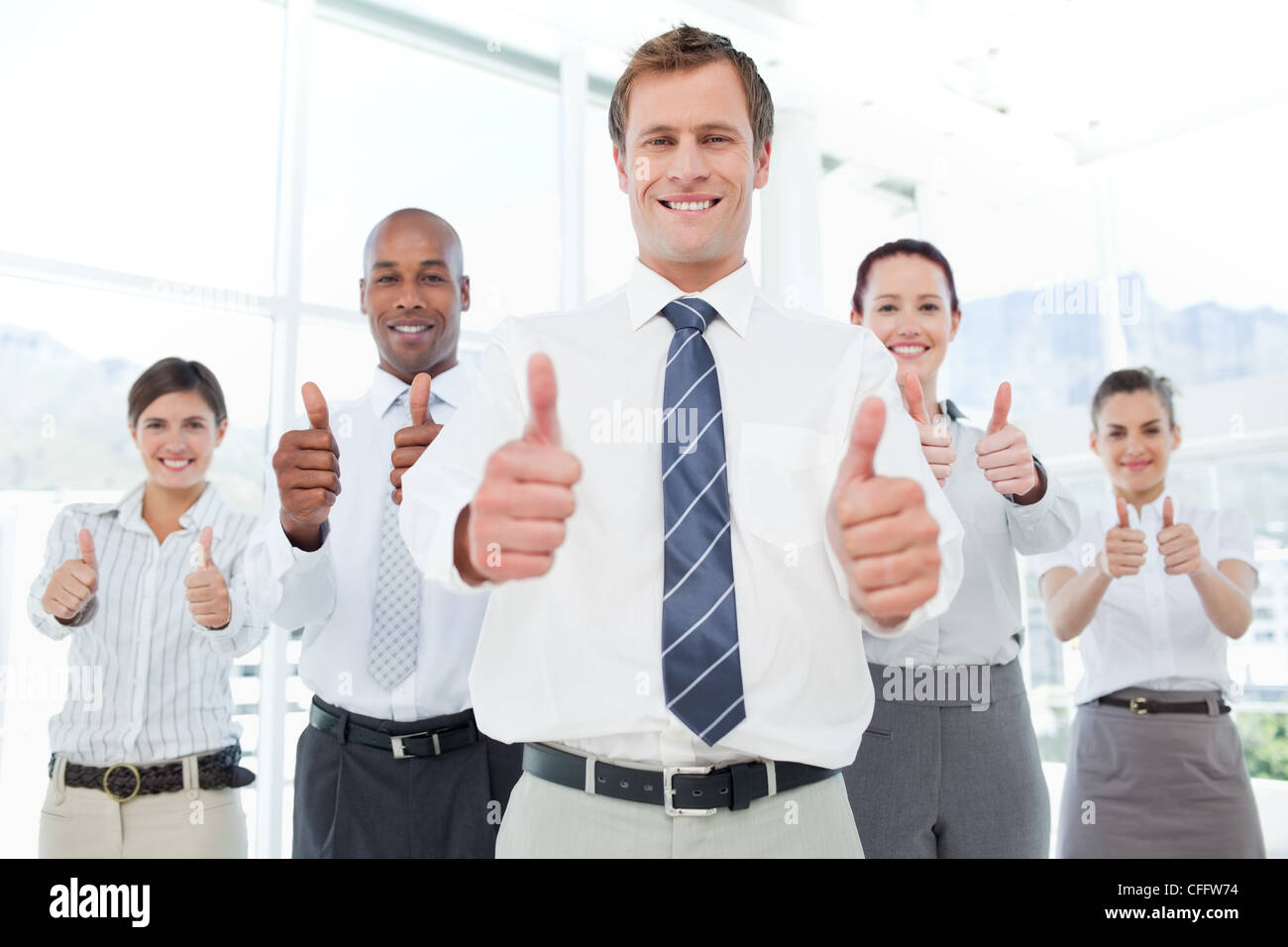 Businessman and his team giving thumbs up Stock Photo - Alamy