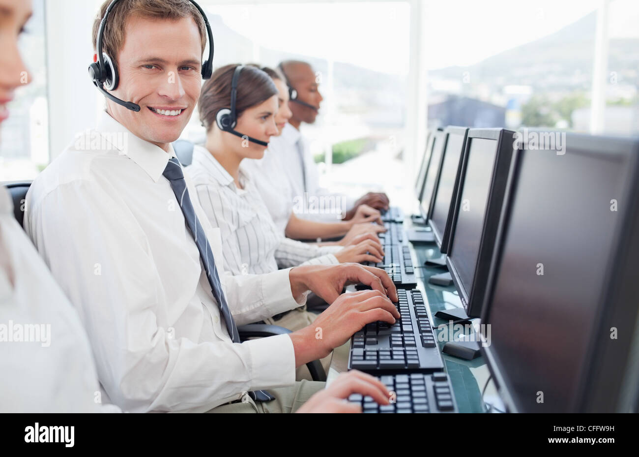 Smiling call center employee sitting among his colleagues Stock Photo ...