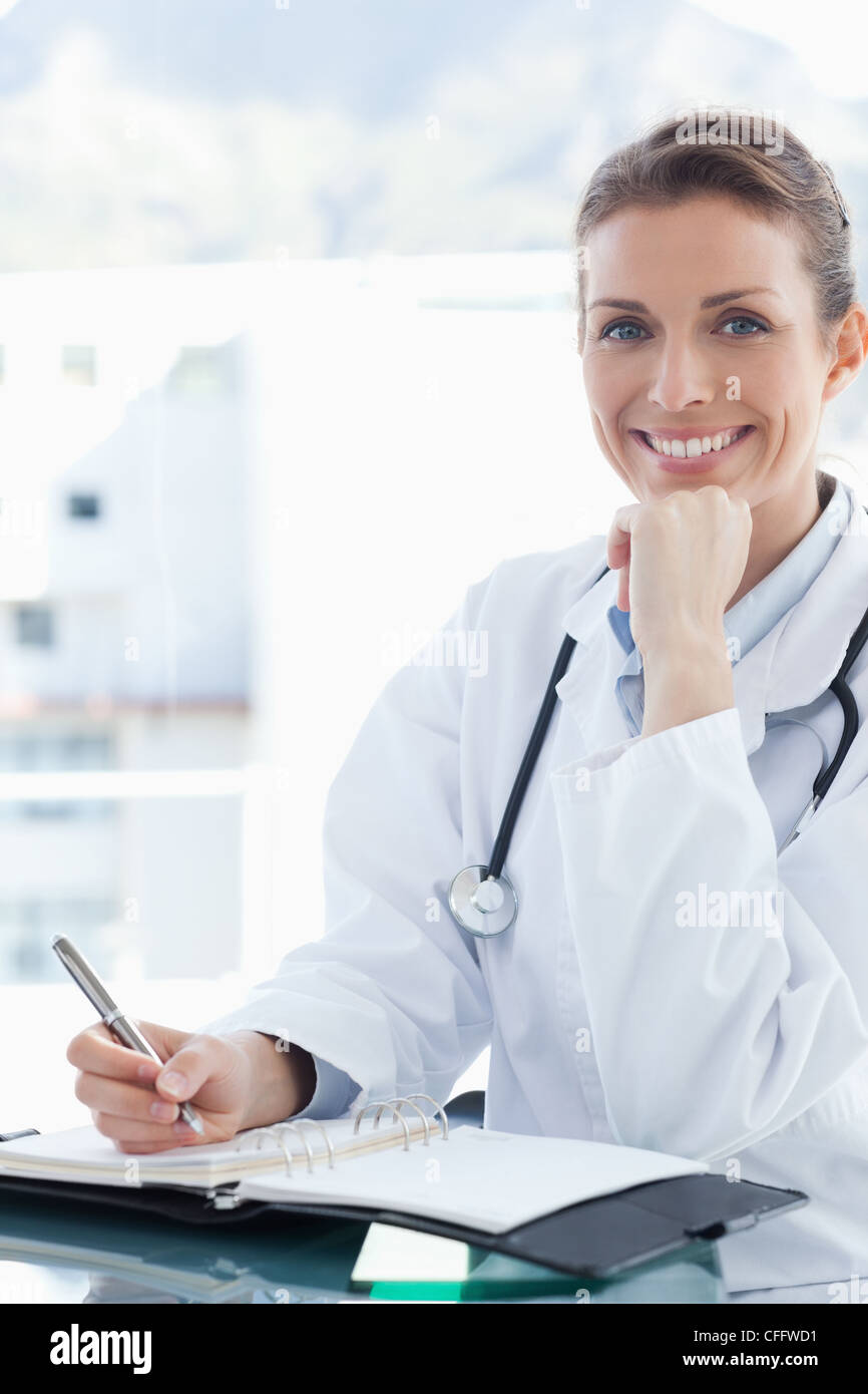 Smiling doctor taking notes on her pocket calendar Stock Photo - Alamy