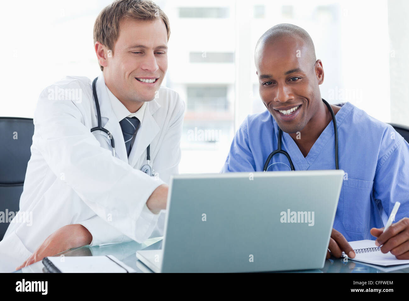 Smiling doctors working with laptop Stock Photo - Alamy