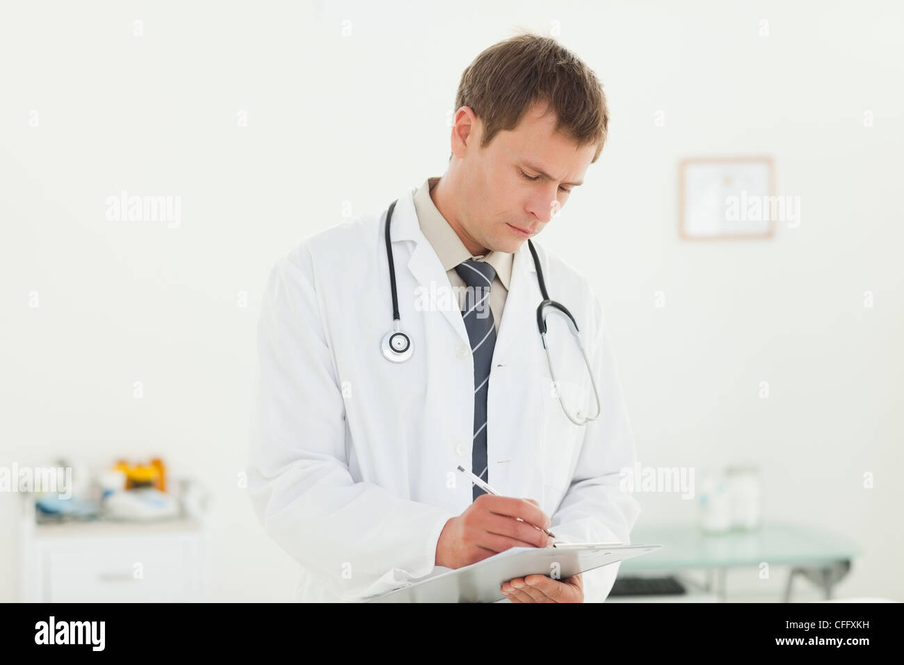 Doctor taking notes on a clipboard in his examination room Stock Photo ...