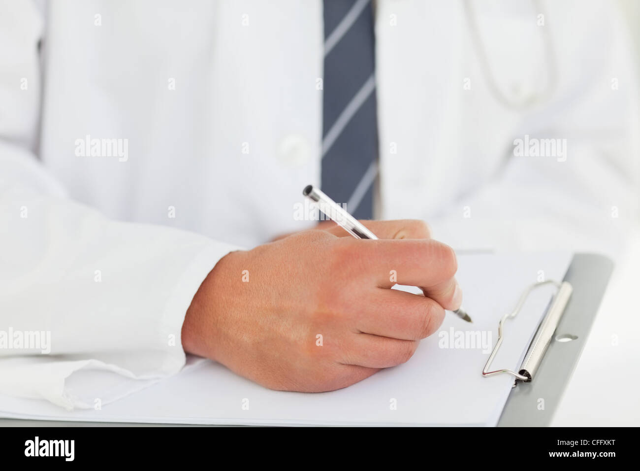 Close up of doctors hand writing on a clipboard Stock Photo - Alamy