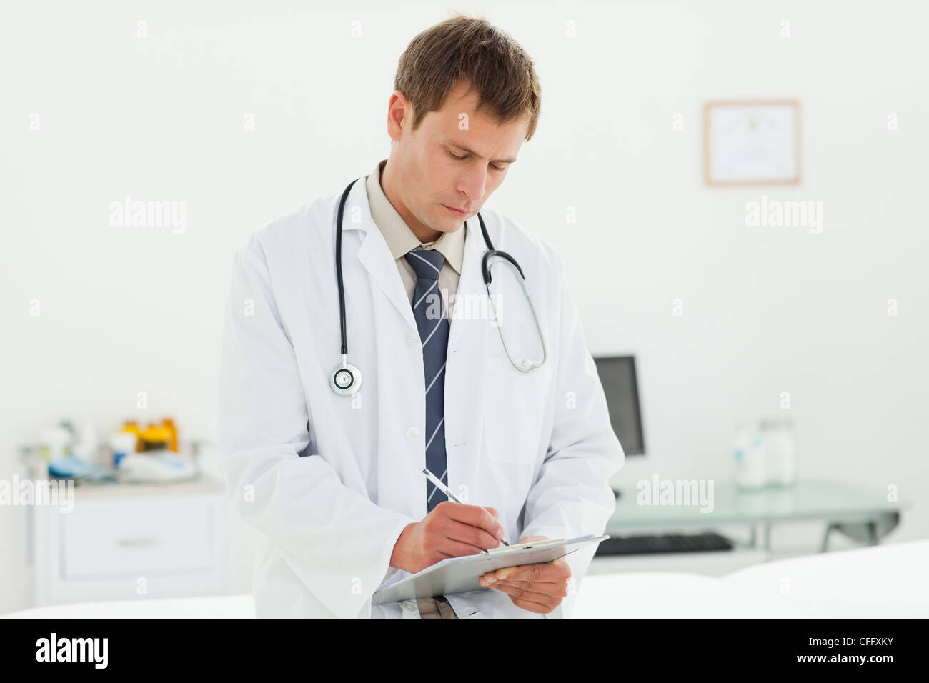 Doctor in examination room taking notes Stock Photo - Alamy