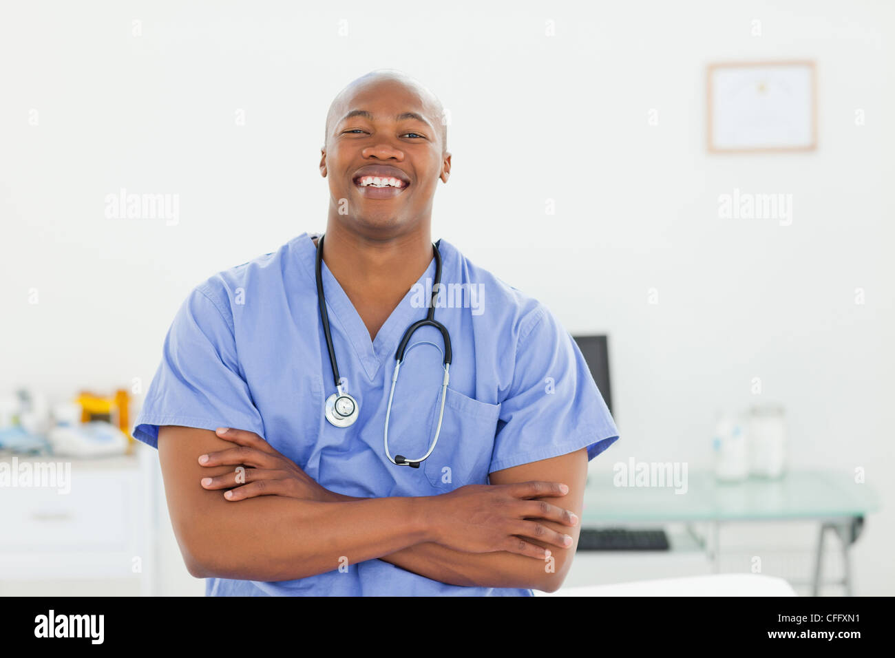 Smiling doctor in scrubs with arms folded in his examination room Stock ...