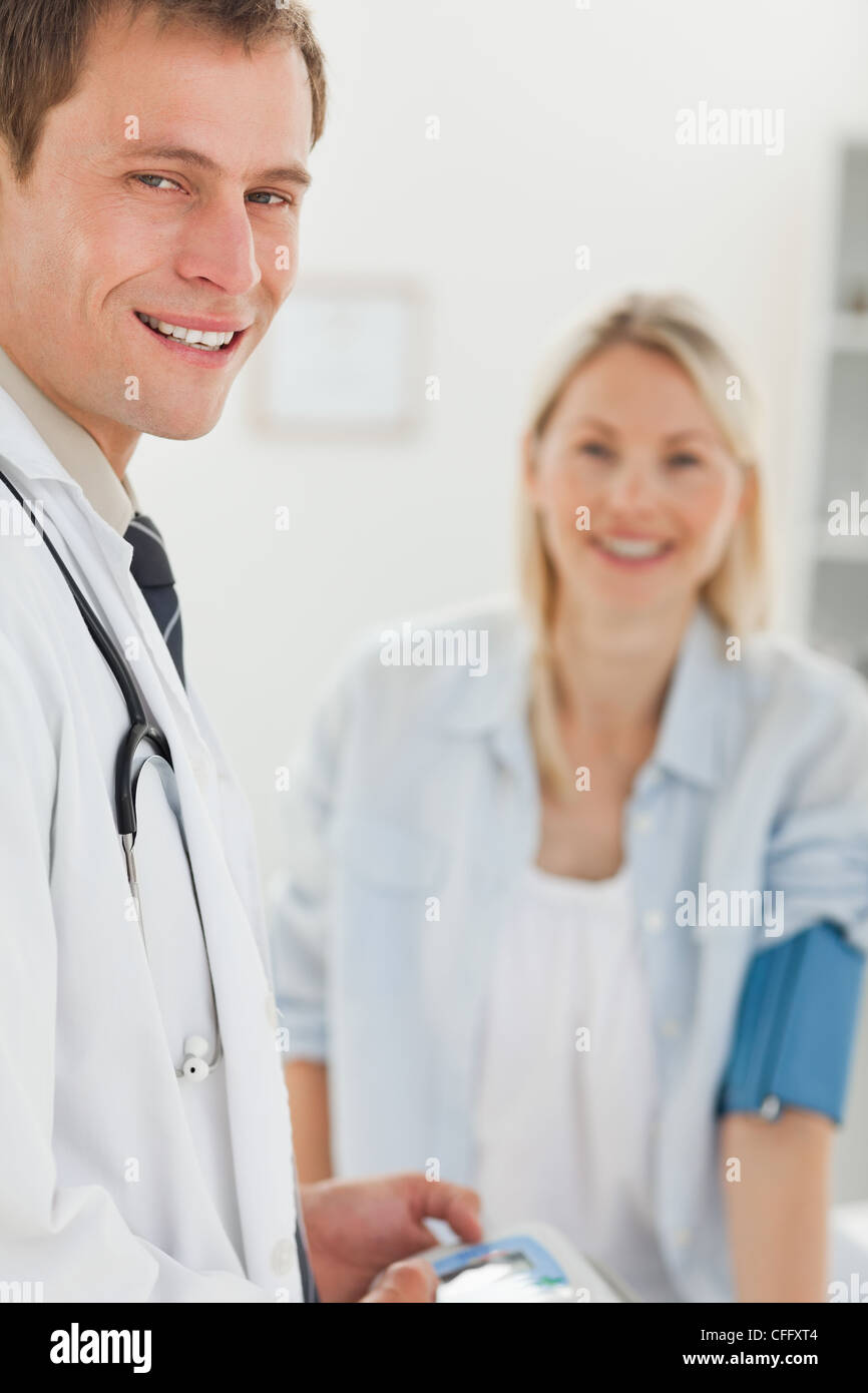 Smiling doctor checking his patients blood pressure Stock Photo - Alamy