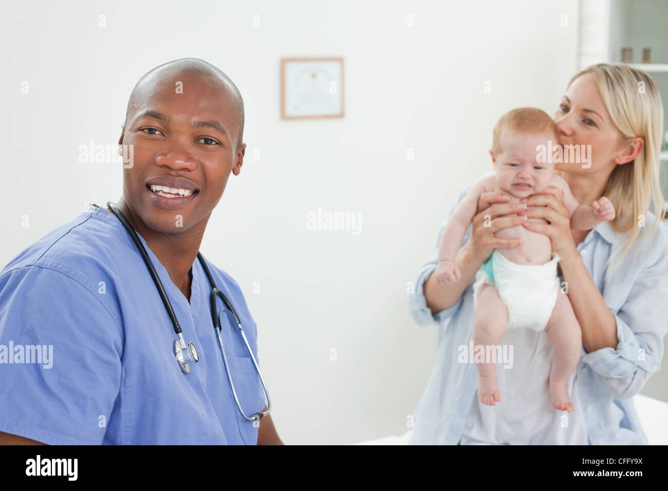 Smiling doctor with mother and her baby next to him Stock Photo - Alamy