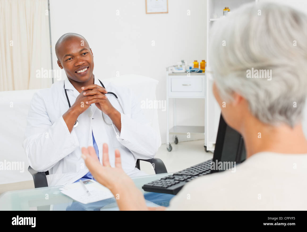 Smiling doctor listening to his patient Stock Photo - Alamy