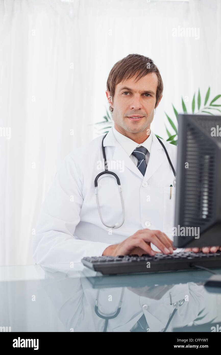 Surgeon sitting at his desk while working on his computer Stock Photo ...