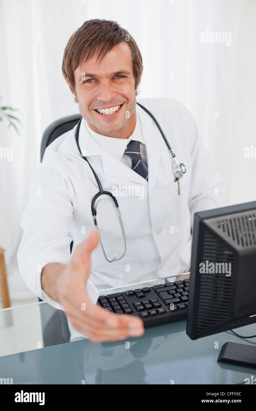 Smiling surgeon offering a handshake while looking at the camera Stock ...