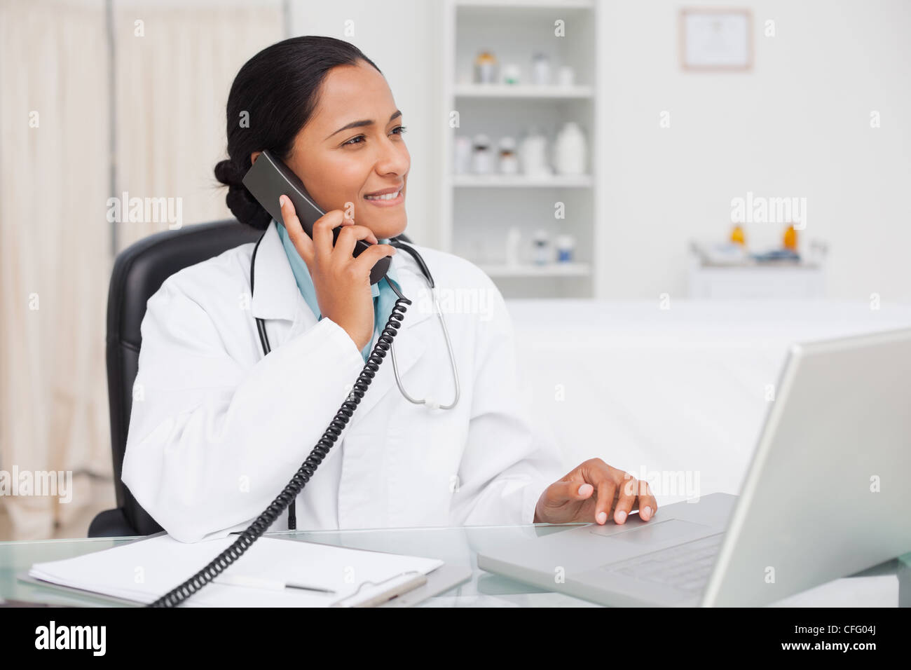 Smiling doctor looking away while talking on her office Stock Photo - Alamy