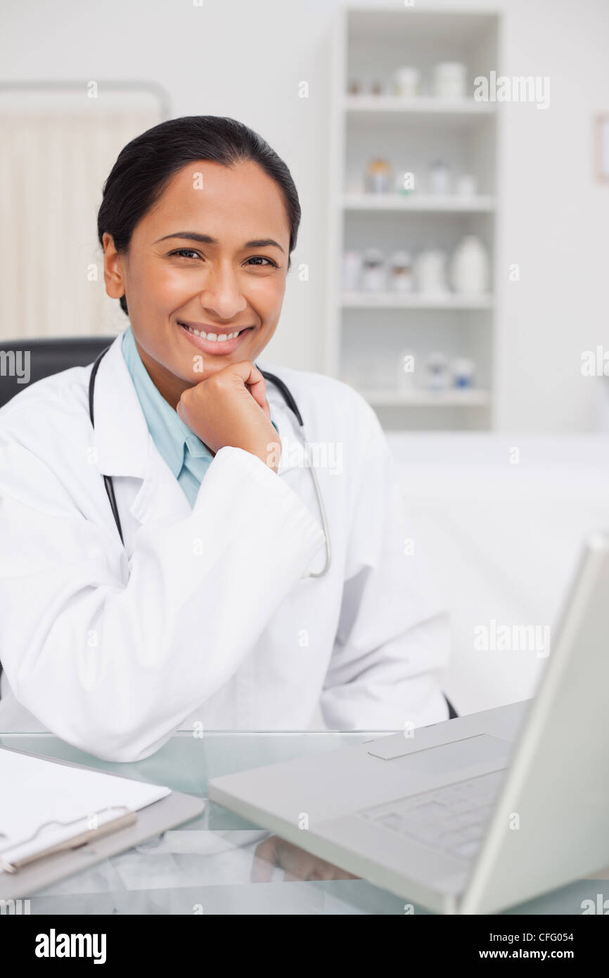 Smiling doctor sitting in front of her laptop Stock Photo - Alamy